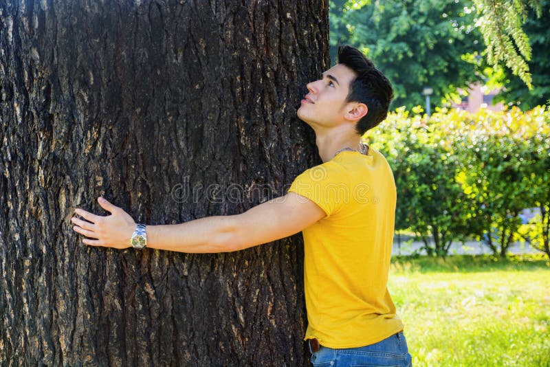 Smiling Young Man Hugging a Tree, Looking Up Stock Photo - Image of ...
