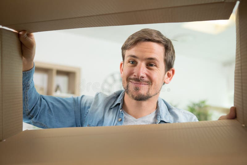 Smiling Young Man Looking into Cardboard Box Stock Image - Image of ...