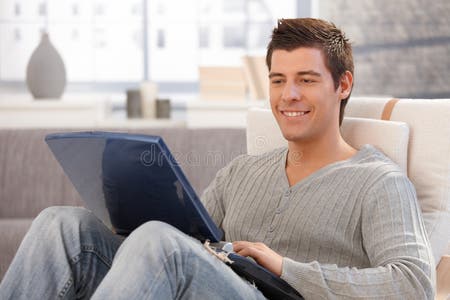 Smiling Young Man Using Computer in Armchair Stock Image - Image of ...