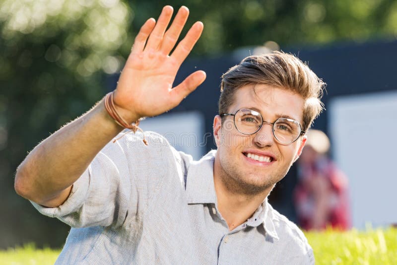 Smiling Young Man Waving while Looking at Camera Stock Photo - Image of ...