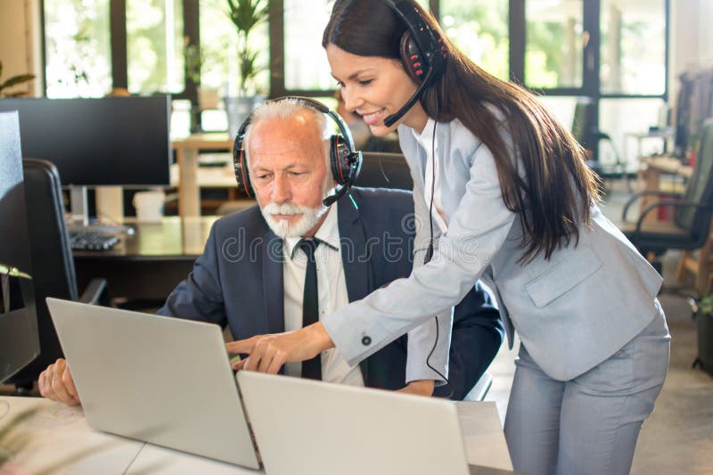 Smiling Young Manager Helping Senior Worker with Computer Work in ...