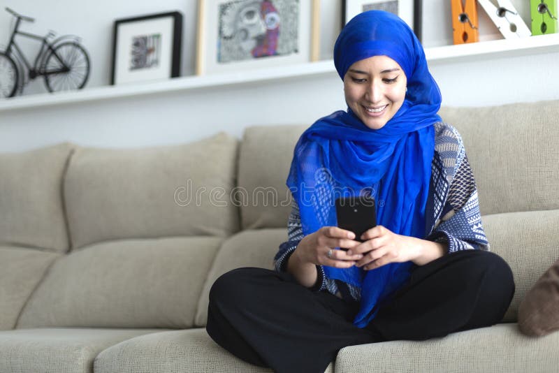 Smiling Young Muslim Woman Using a Smart Phone at Home Stock Image ...