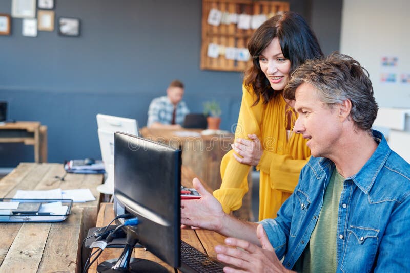 Smiling Young Office Colleagues Talking Together Over a Computer Stock ...