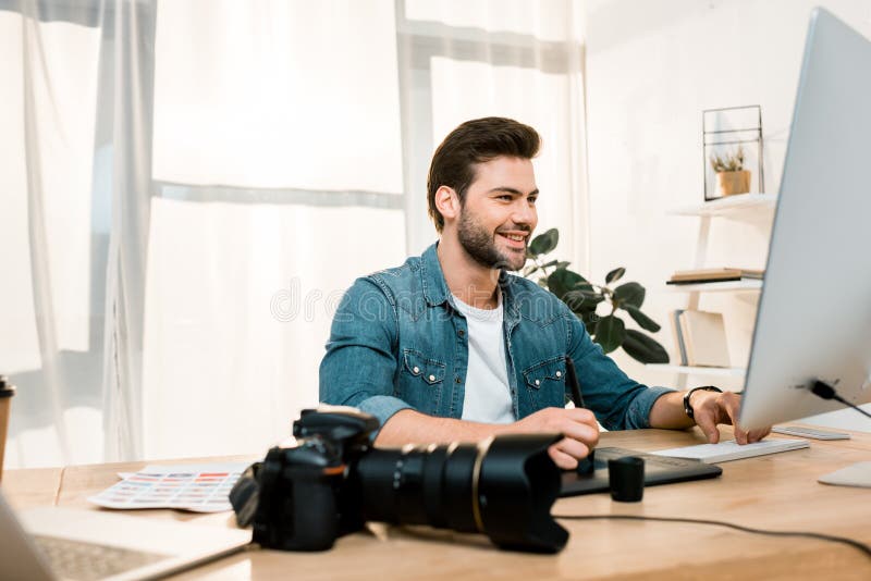 Smiling Young Photographer Using Desktop Computer and Retouching Photos ...