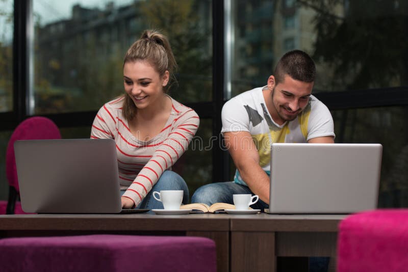 Smiling Young Students in Cafe Using Laptop Stock Photo - Image of ...