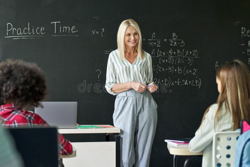 Smiling Young Teacher Having Mathematics Lesson Standing at Chalkboard ...