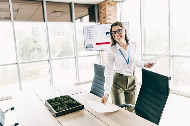 Smiling Young Trainee in an Office Setting Arranging Documents in a ...