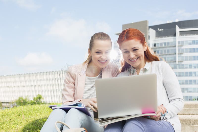 Smiling Young University Students Using Laptop with Buildings in ...