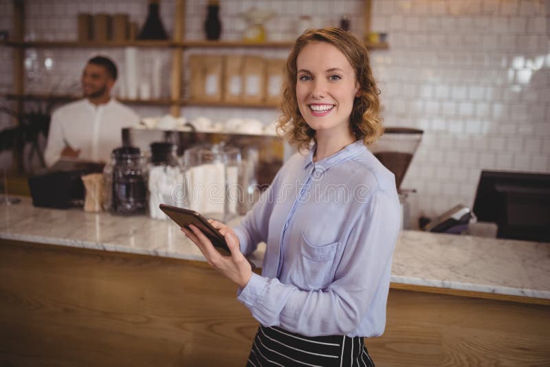 Smiling Young Waitress Using Digital Tablet while Standing by Counter ...