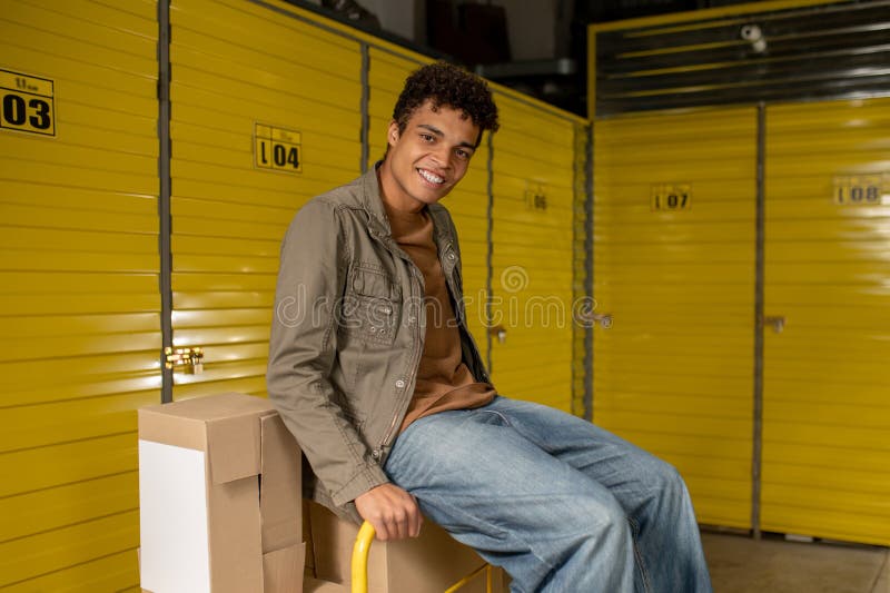 Smiling Young Warehouse Worker Sitting on the Box and Resting Stock ...