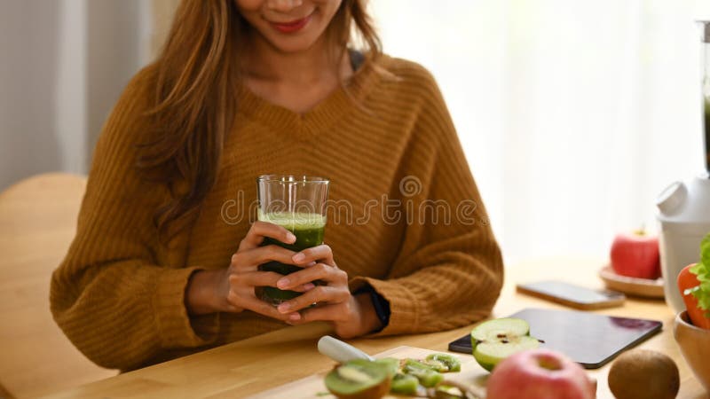 Smiling Woman Holding Glass Of Healthy Green Vegetable Smoothie In Her