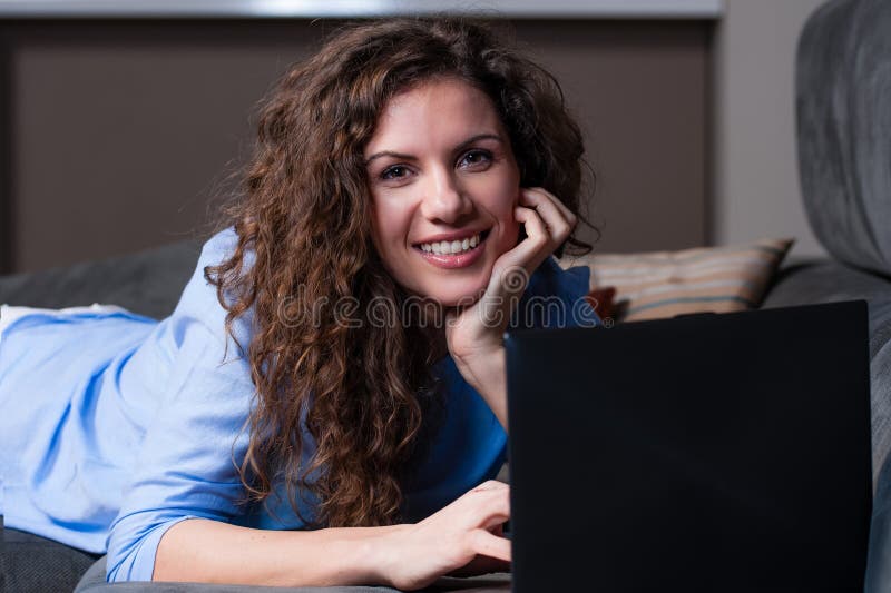 Smiling Young Woman Laying on Couch and Using Laptop. Stock Image ... Smiling Young Woman Laying on Couch and Using Laptop. Stock Image ...