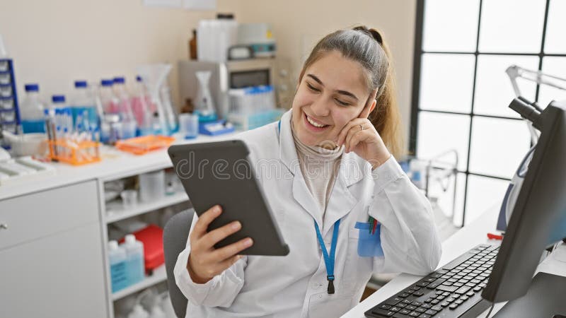 Smiling Young Woman in White Lab Coat Using Tablet in a Laboratory ...