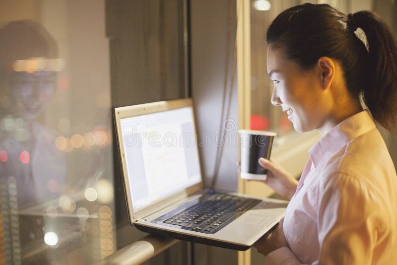 Smiling Young Woman Working in the Office on Her Laptop at Night Stock ...