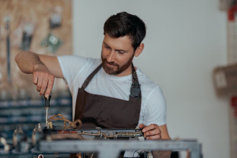 Smiling Young Worker Repairing Coffee Machine in a Workshop Stock Photo ...