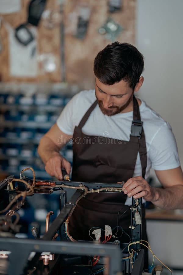 Smiling Young Worker Repairing Coffee Machine in a Workshop Stock Photo ...