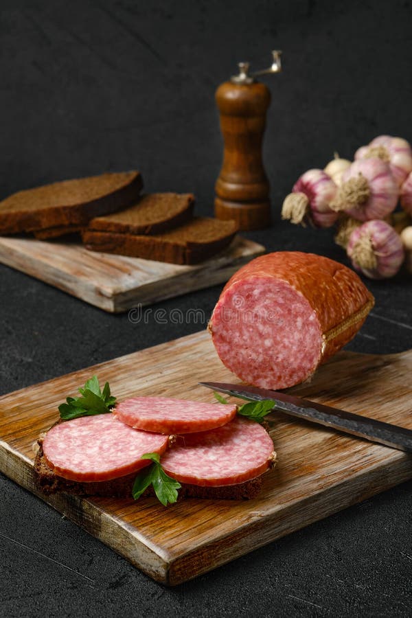 Smoked Salami and Sandwich on Cutting Board Over Black Background Stock ...