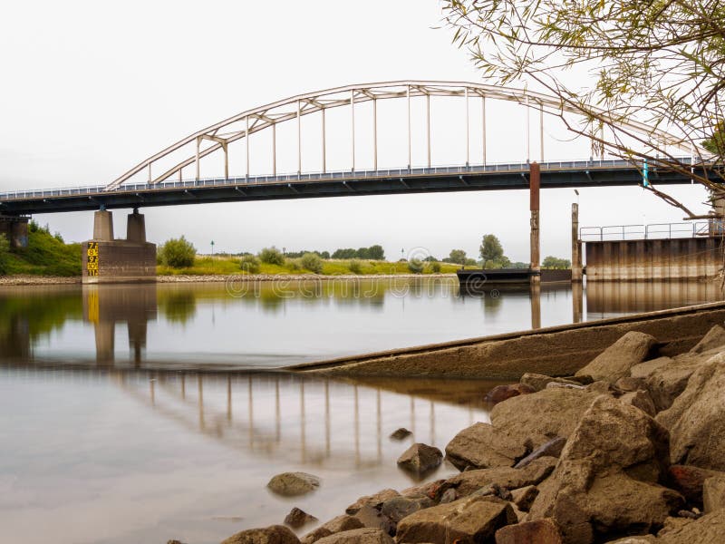 Smooth Water Looking Past Rocks at a Bridge Across a River Stock Image ...