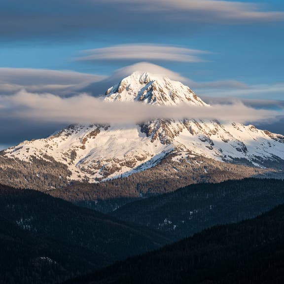 Snow-capped Mountain Peaks Under a Clear Blue Sky, Partially Enveloped ...