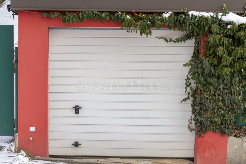 Snow-Covered Garage Door with Red Wall and Green Ivy Stock Image ...
