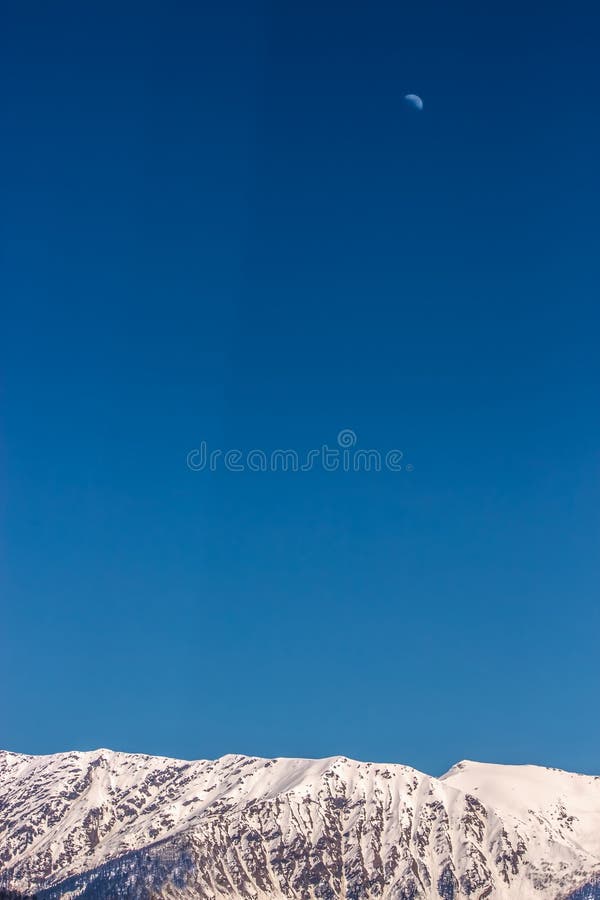 Snow-covered Mountain Range Under a High Blue Sky and the Moon Stock ...