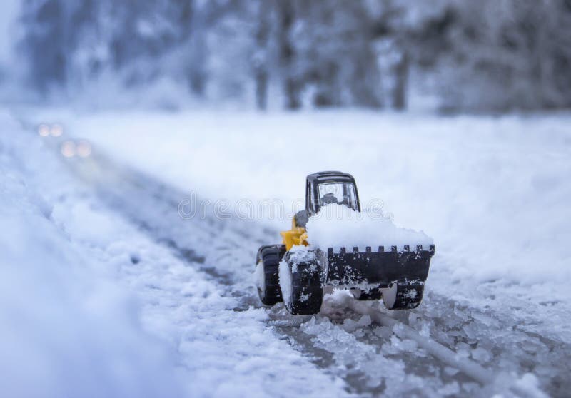 On Snow-covered Road Tractor Clears Snow Twilight Headlight Lights in ...