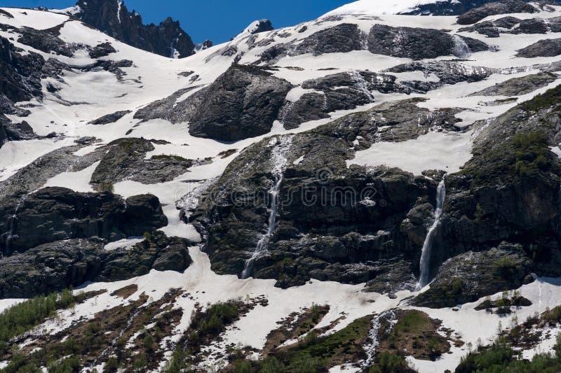 Snow-covered Rocky Mountain Slopes with Multiple Waterfalls Stock Photo ...