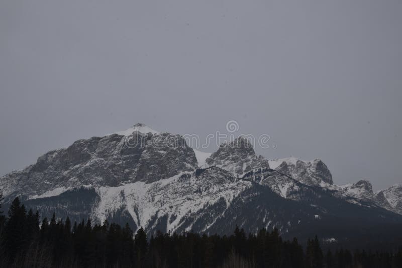 Snow Covered Rocky Mountains with Hazy Grey Sky Stock Photo - Image of ...