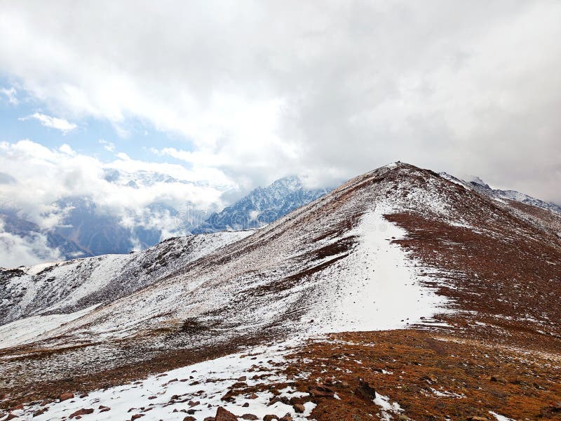 Snow-dusted Mountain Ridge with Rugged Terrain Under a Cloudy Sky Stock ...