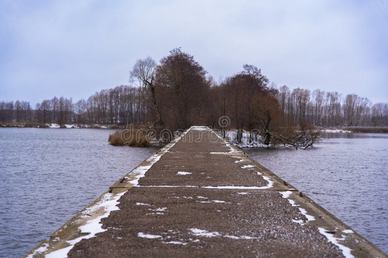 Snow-dusted Pathway Extending into a Lake on a Cloudy Winter Day Stock ...