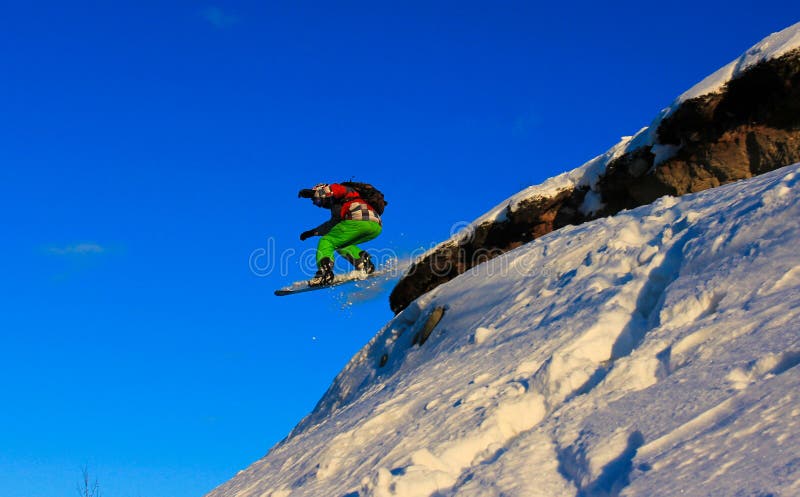 Snowboard jump off a cliff stock photo. Image of slide - 141577796
