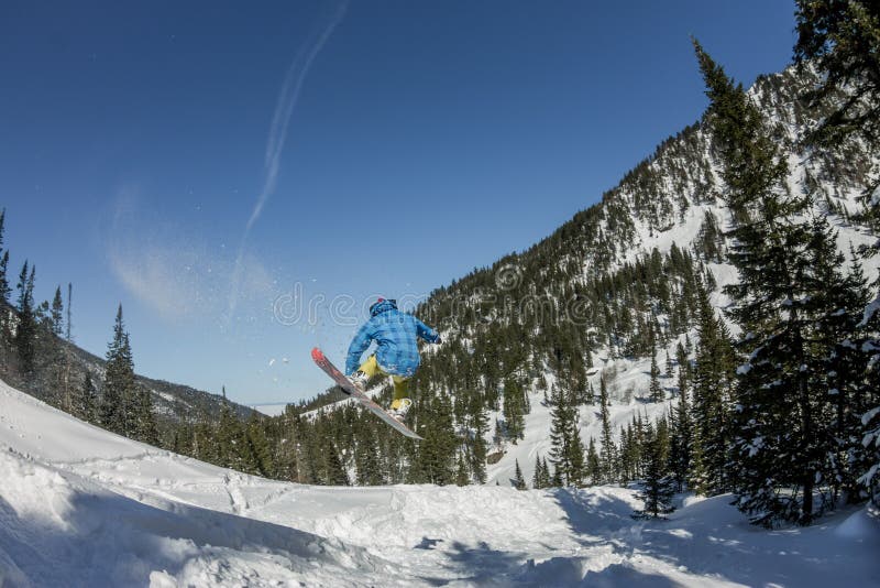 Snowboarder Freerider Jumping from a Snow Ramp in the Sun on a ...