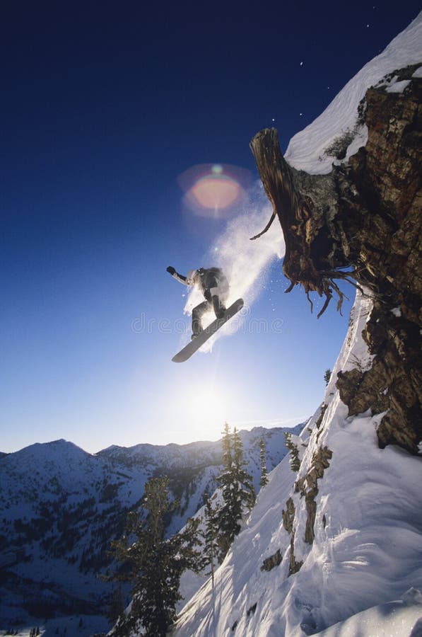 Snowboarder Jumping from Mountain Ledge Stock Photo - Image of ...