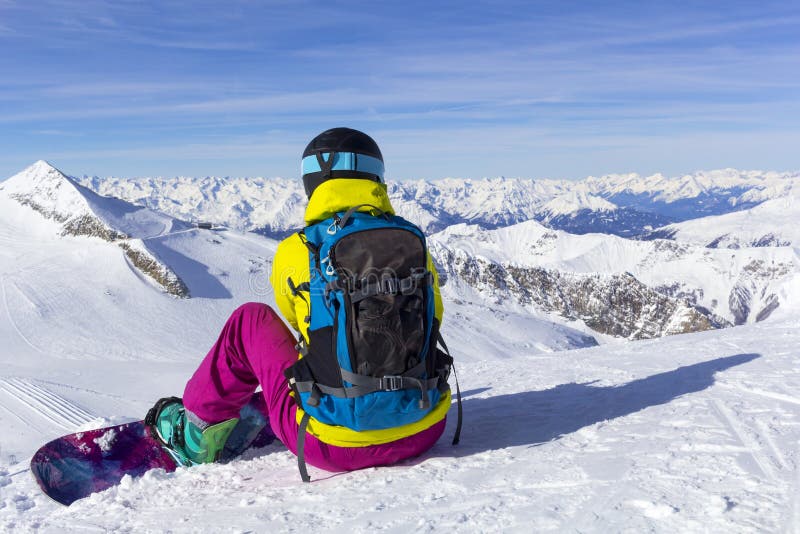 Snowboarder Sits on a Slope with Her Back and Looks at the Panorama of ...