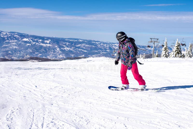 Snowboarder Sliding Down the Hill with Ski Lift in the Background ...