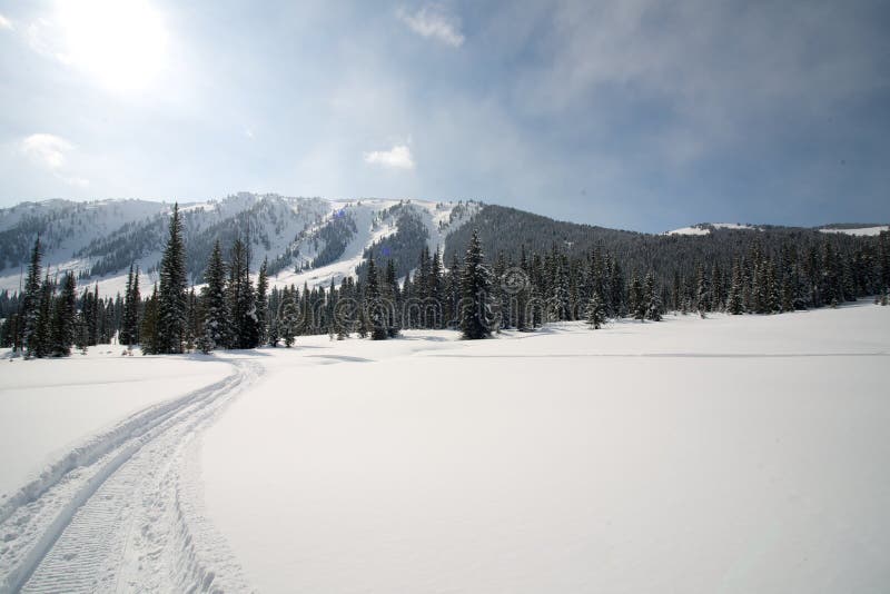 Snowmobile Track Mark on the Snow Against Mountains and a Blue Sky ...
