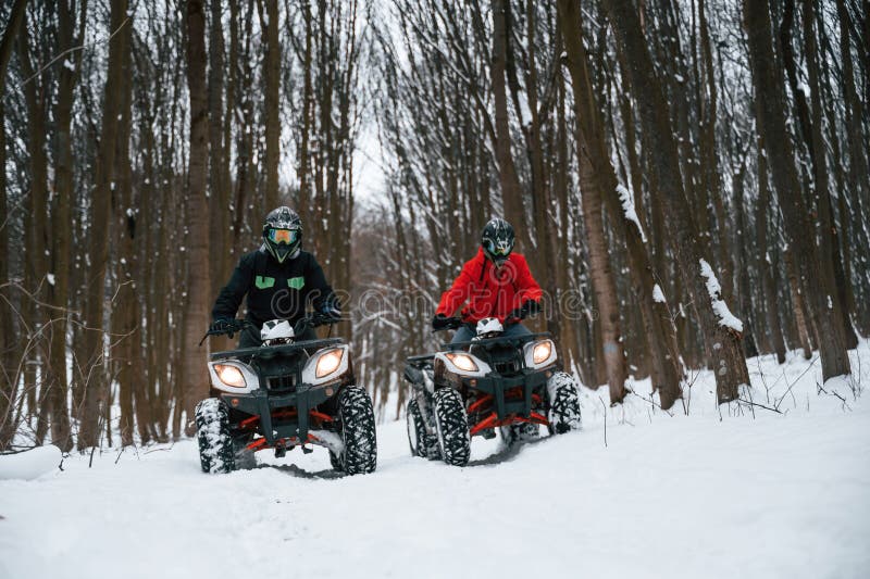 On the Snowy Ground. Two People are Riding ATV in the Winter Forest ...