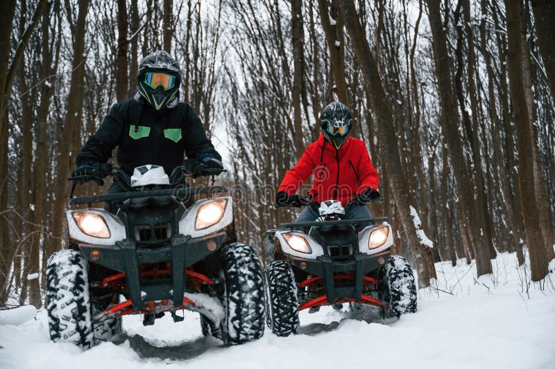 On the Snowy Ground. Two People are Riding ATV in the Winter Forest ...