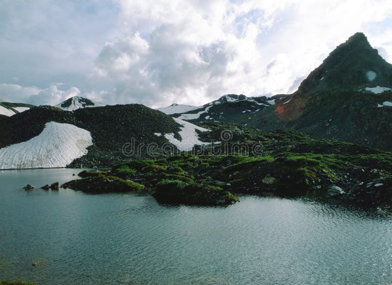 Snowy Hilly Landscape with a Lake in the Foreground with Sunlight ...