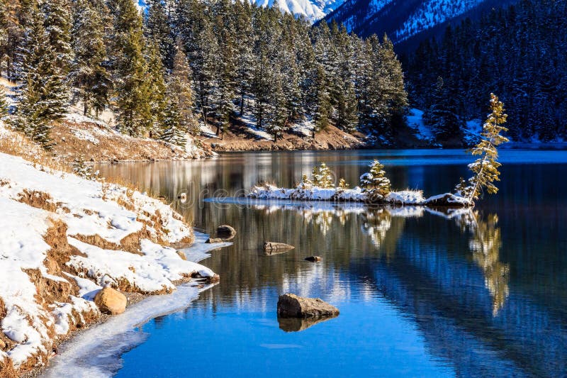A Snowy Landscape with a Body of Water and Trees Stock Photo - Image of ...