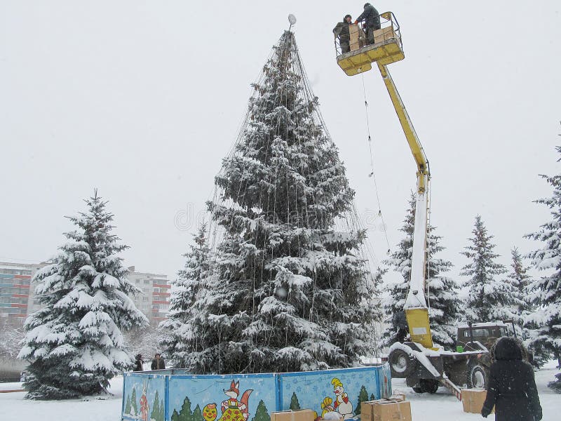 A Snowy Outdoor Scene with a Decorated Christmas Tree, Workers Using a ...