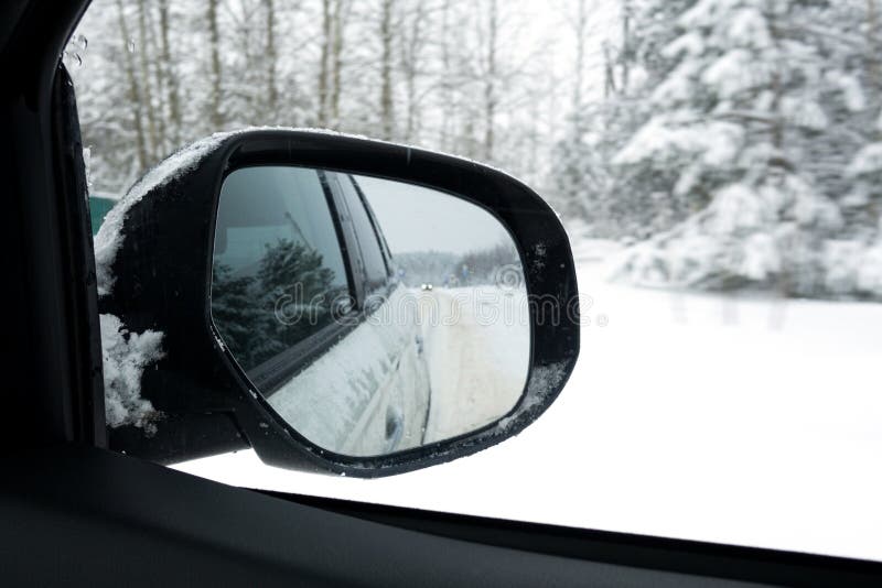 Snowy Road and Forest from the Side Mirror of the Car. View from the ...