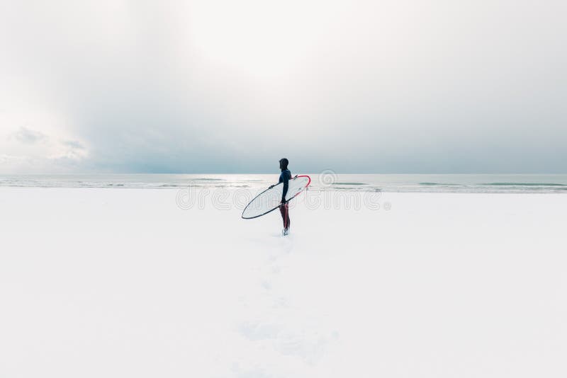 Snowy Winter and Man Surfer with Surfboard. Winter Coastline and Surfer ...