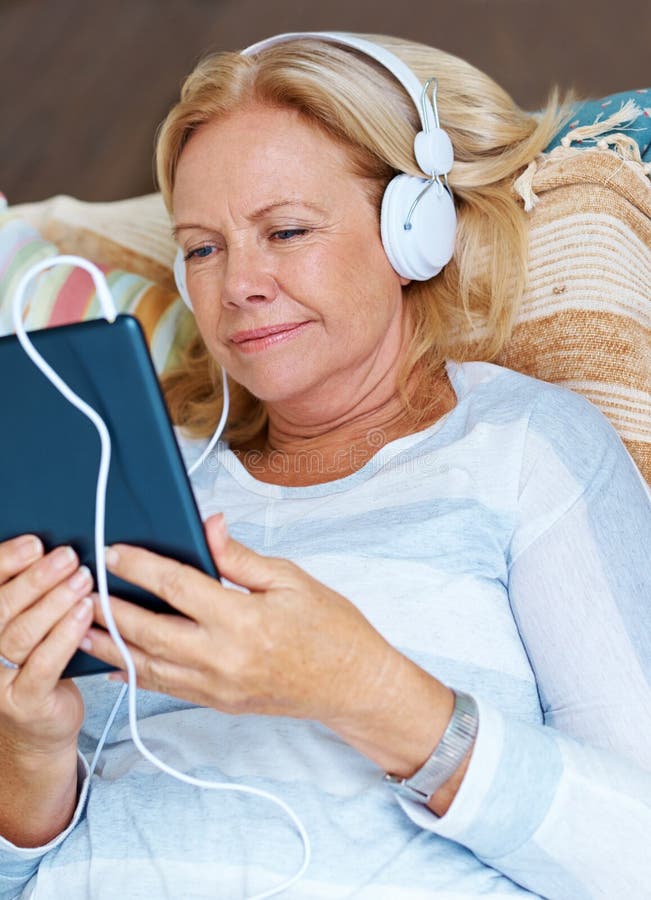 Soapies on the Move. a Senior Woman Looking at Her Digital Tablet while ... Soapies on the Move. a Senior Woman Looking at Her Digital Tablet while ...