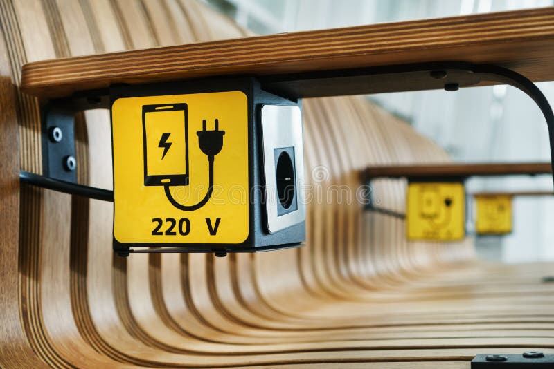 A Socket with a Device Charging Sign on a Wooden Bench at the Airport ...