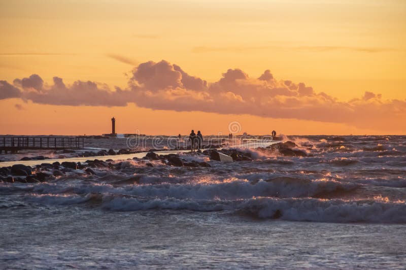 Sunset in Orange Sky Over Mole. Silhouettes of People Walking on the ...