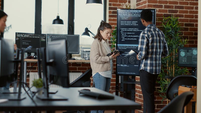 Software Developer Holding Digital Tablet Analyzing Code on Wall Screen Tv Explaining Errors To ...