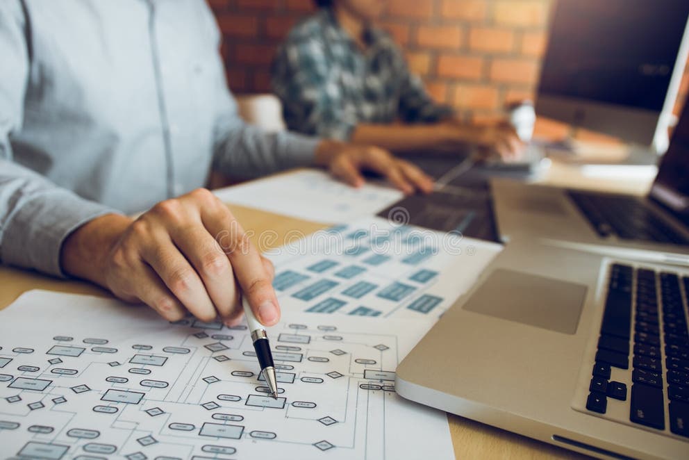 Software Developer is Pointing To the Paper Working and Analyzing Together the Code Written into ...