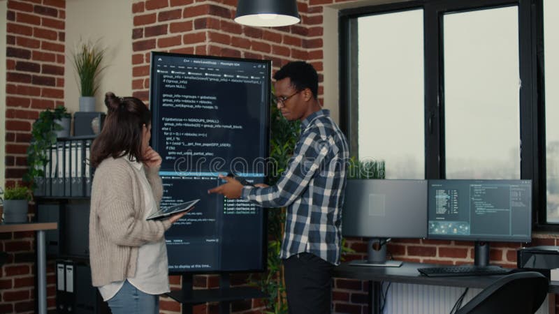 Software Developers Analyzing Source Code On Wall Screen Tv Comparing Errors Using Digital