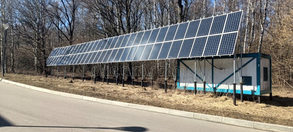 A Solar Panel Array Stands Next To a Small Utility Building in a Wooded ...